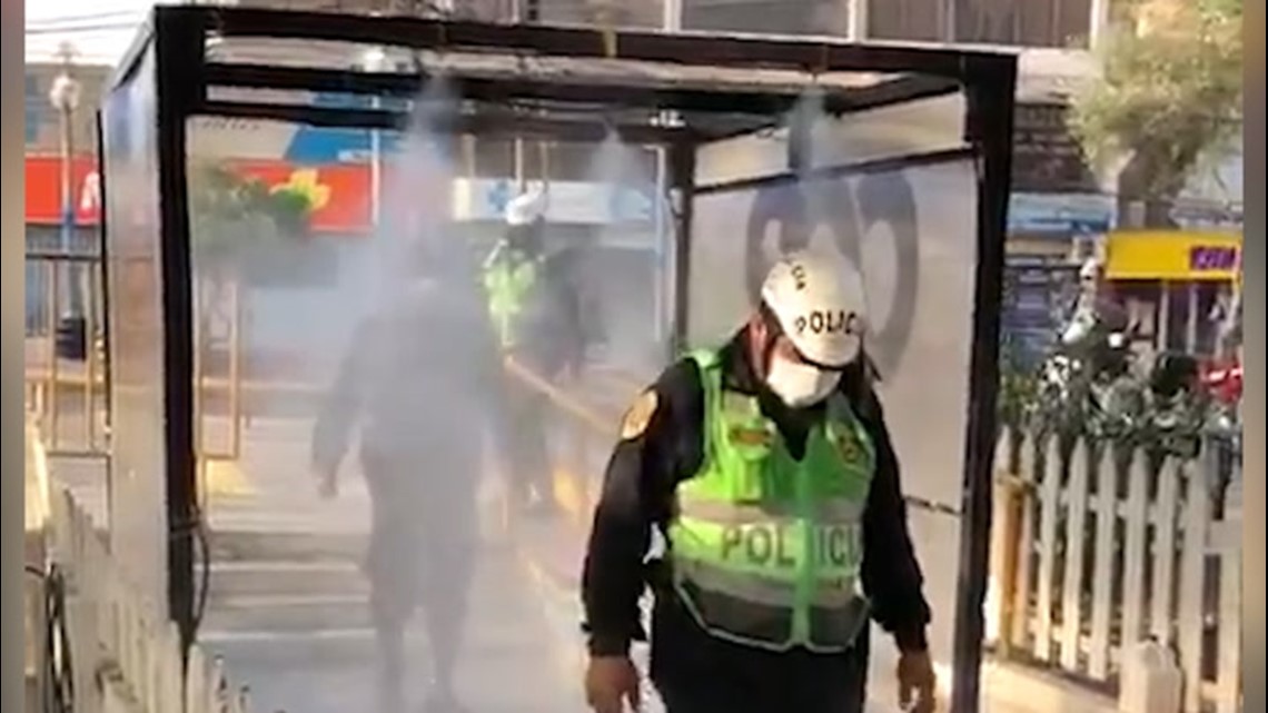 Police officers walk through decontamination booth | newswest9.com